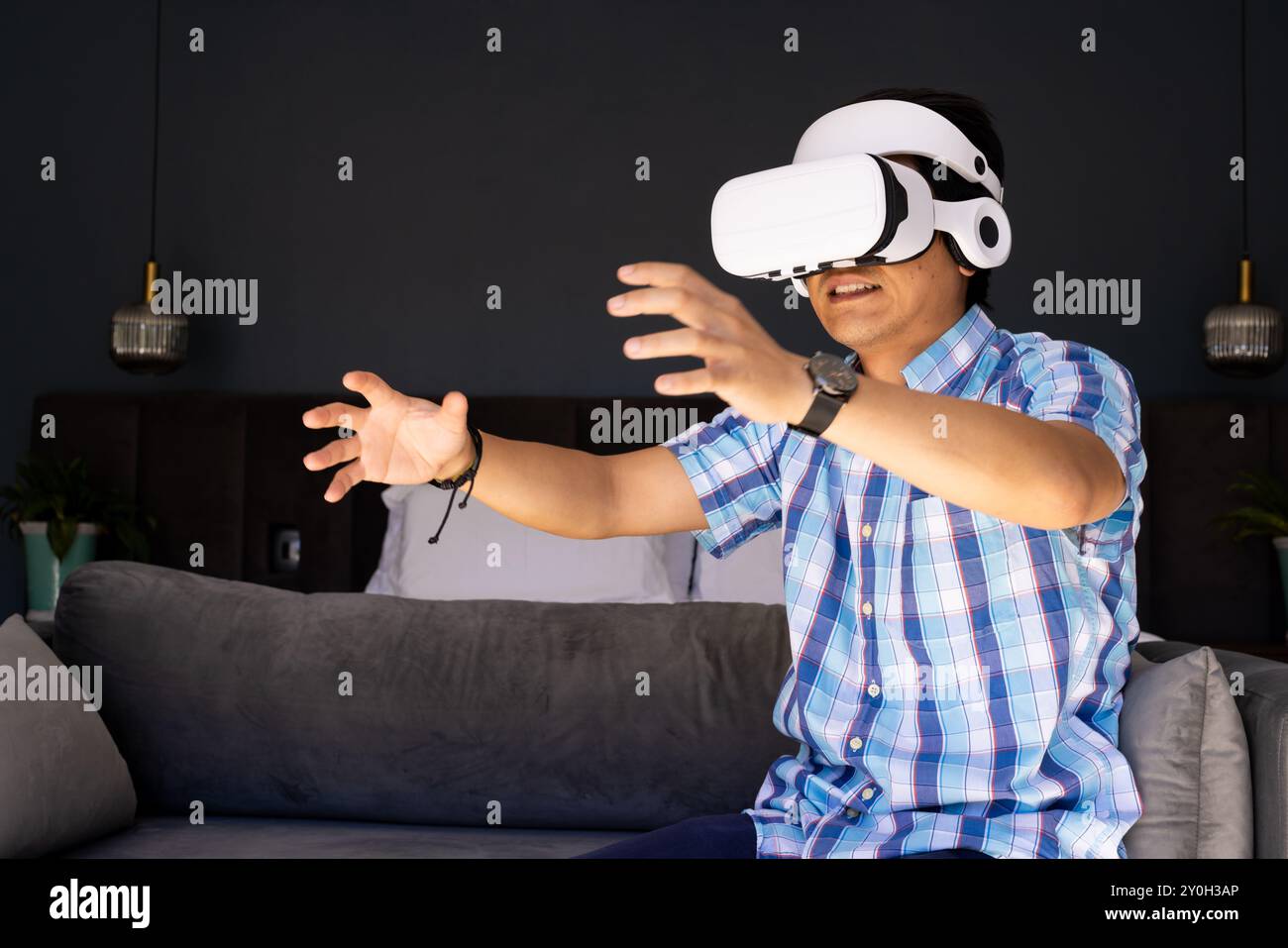 Using VR headset, asian man sitting on couch and experiencing virtual ...