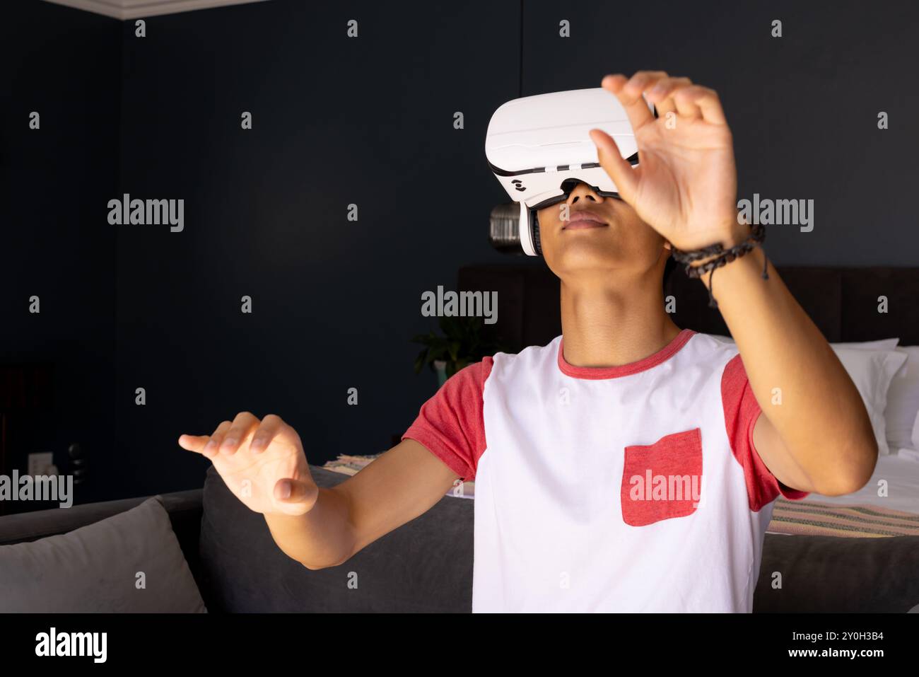 Using VR headset, young person exploring virtual reality in bedroom ...