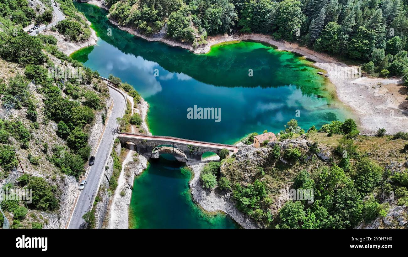 Aerial view of an old bridge connecting two sides of a turquoise lake ...