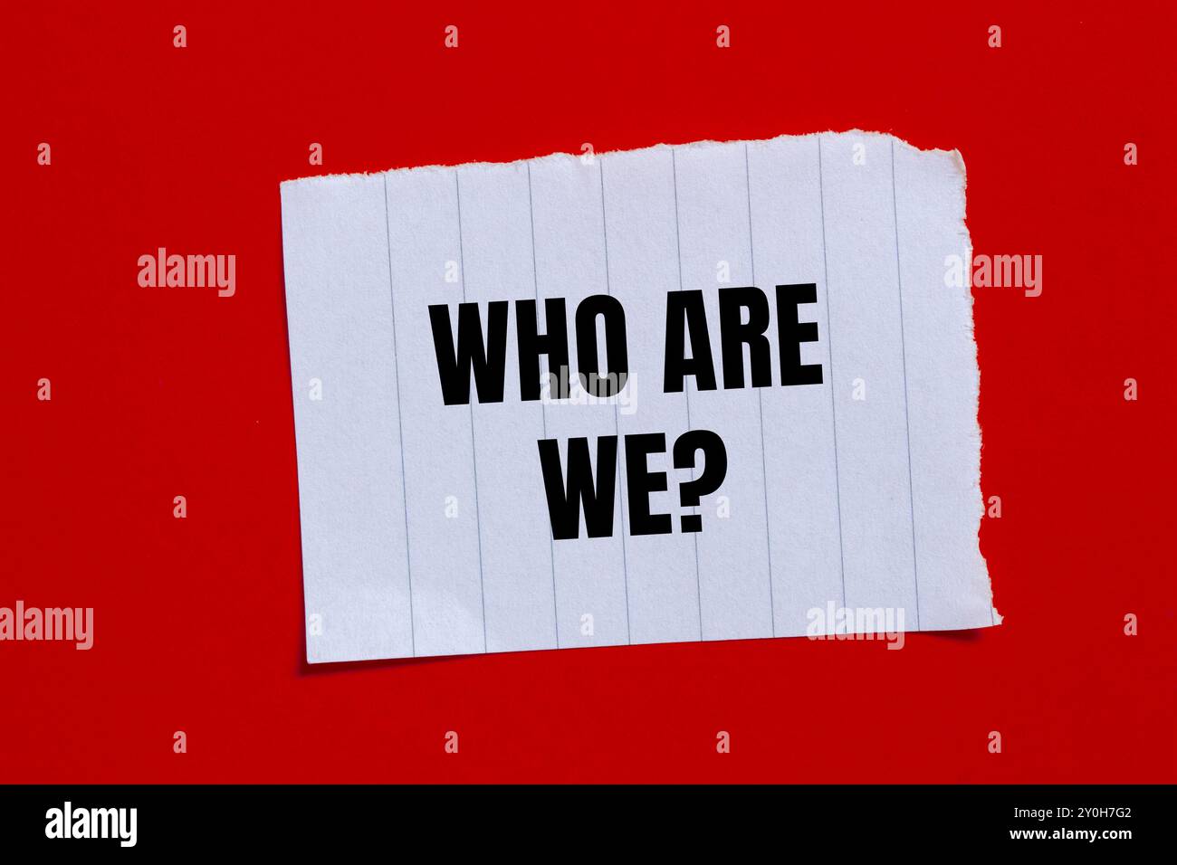Who are we question written on ripped torn paper piece with red ...