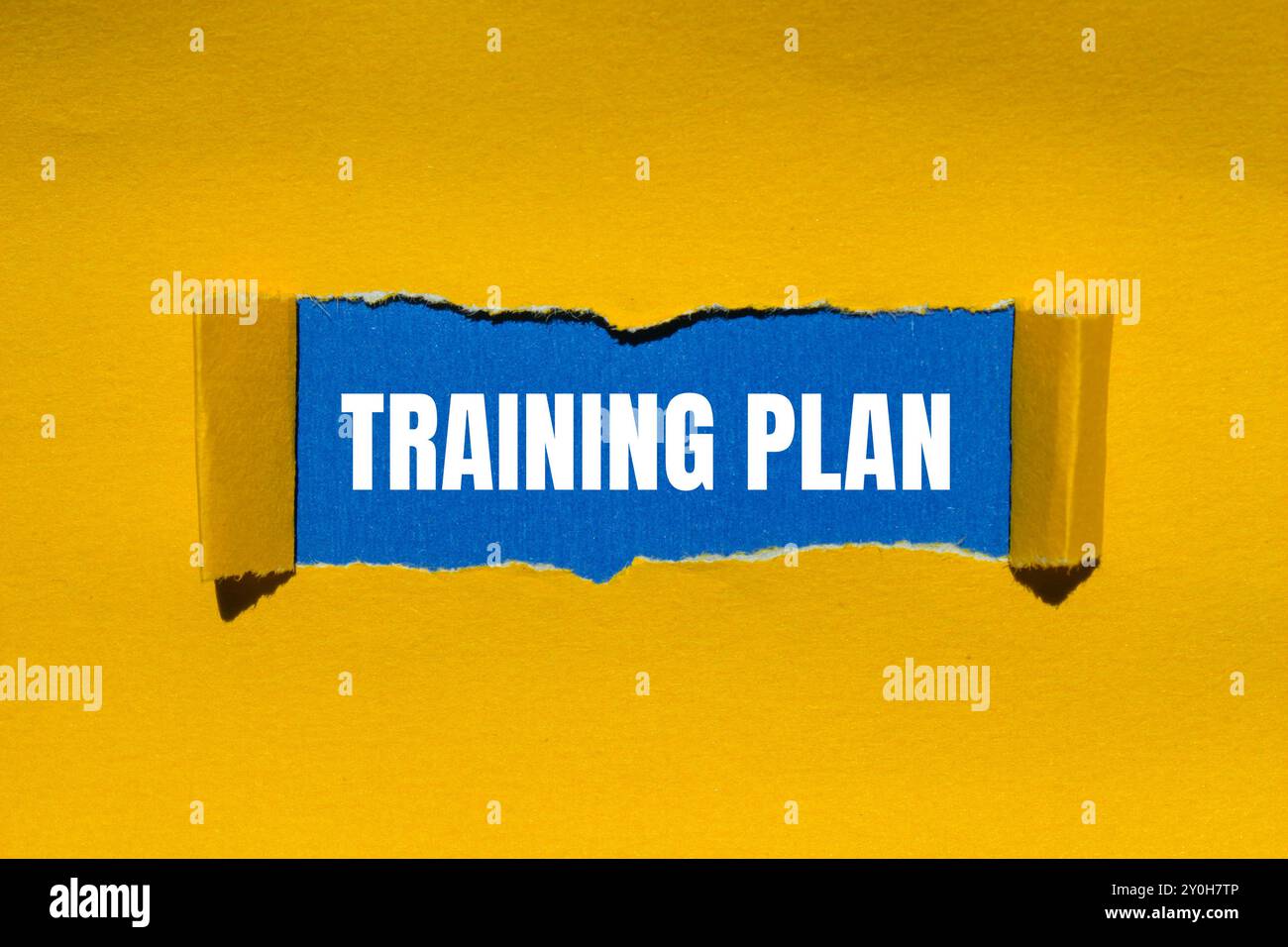 Training plan message written on ripped torn yellow paper with blue ...