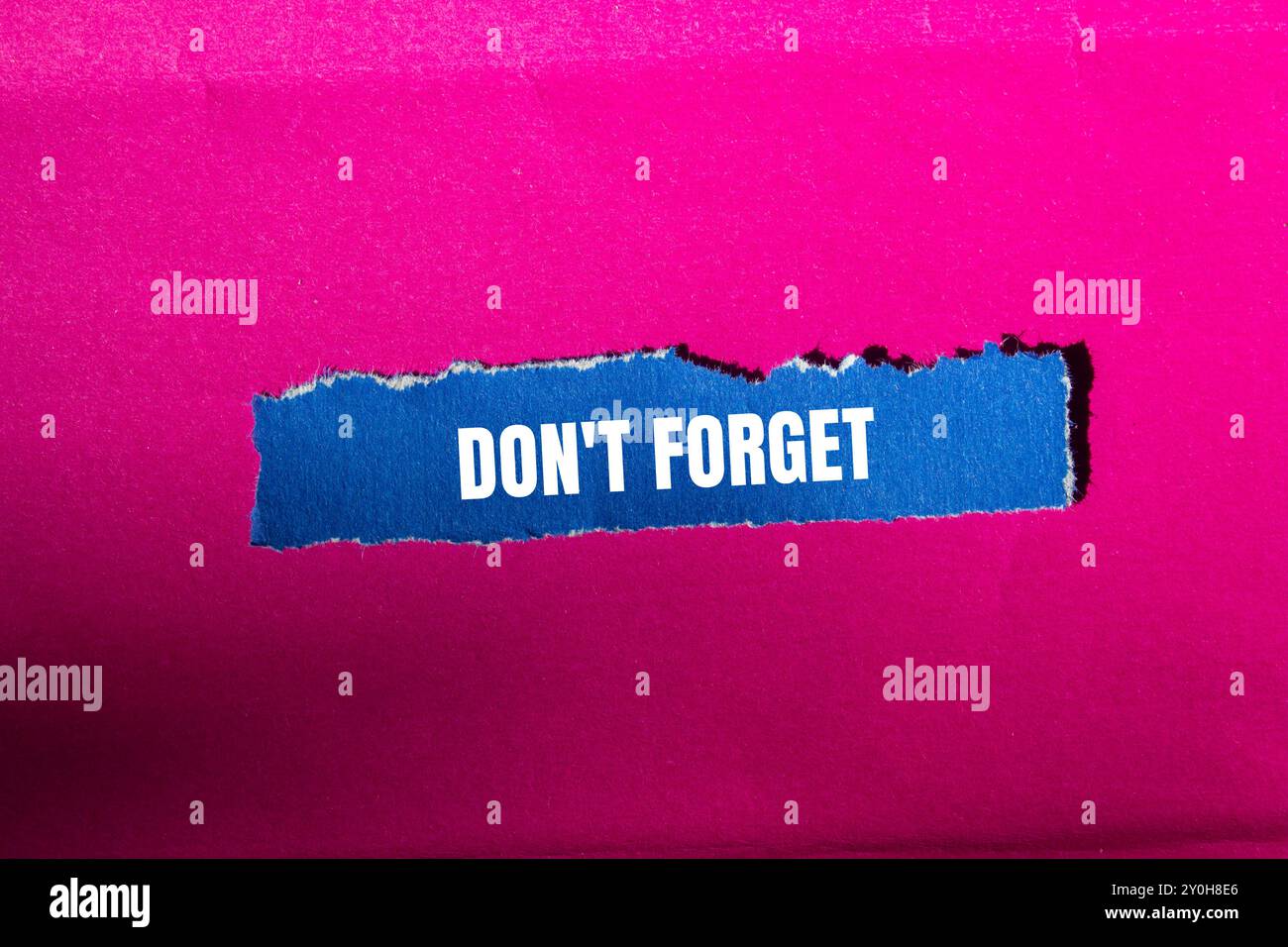Don't forget message written on ripped torn blue paper piece with pink ...