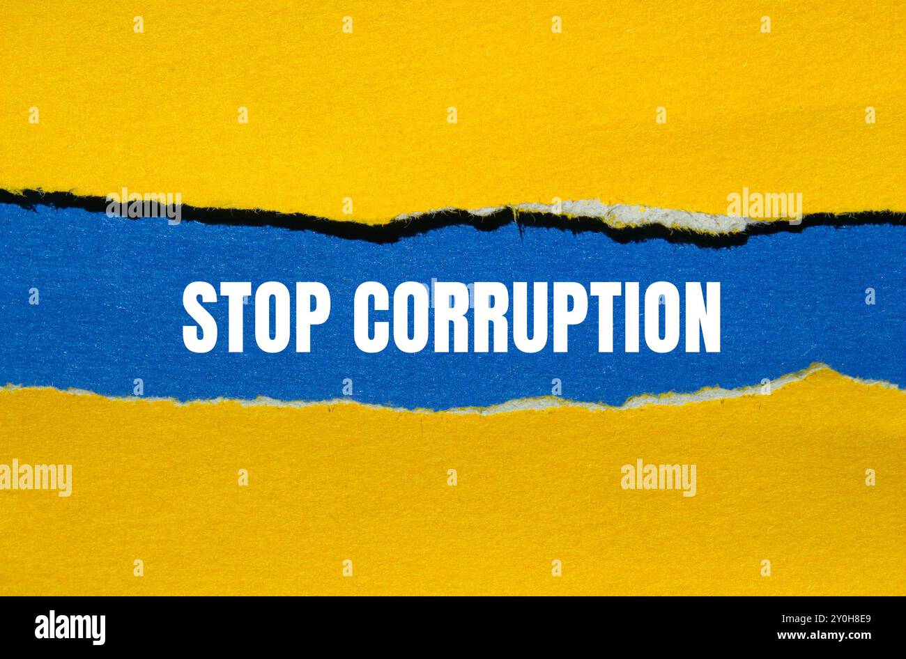 Stop corruption message written on ripped torn yellow paper with blue ...