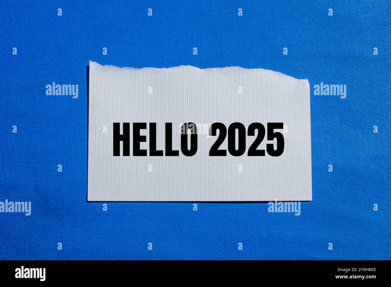 Hello 2025 message written on ripped white torn paper piece with blue background. Conceptual ...