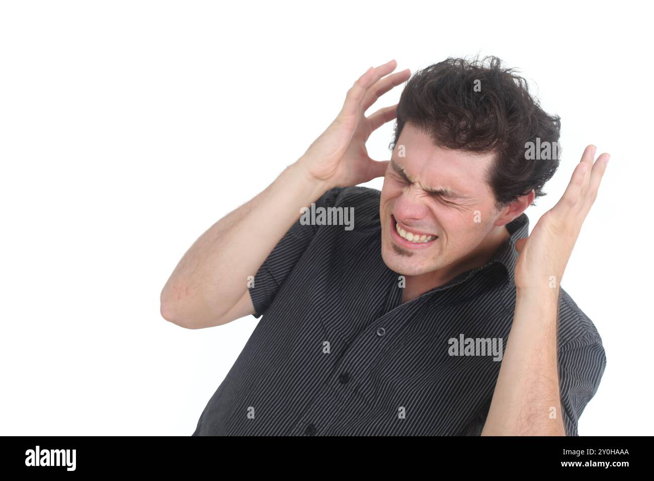 Frustrated and stressed young man holding head in hands while standing ...