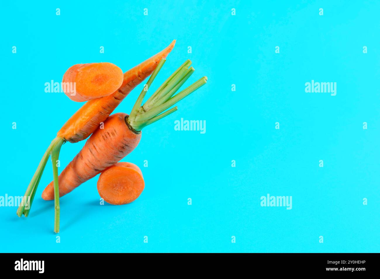 Whole and cut fresh carrots on light blue background, space for text ...