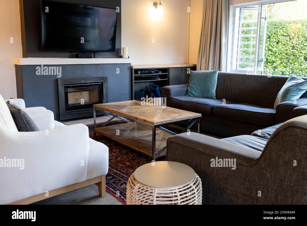 Modern living room with cozy sofas, flat-screen TV, and large windows ...