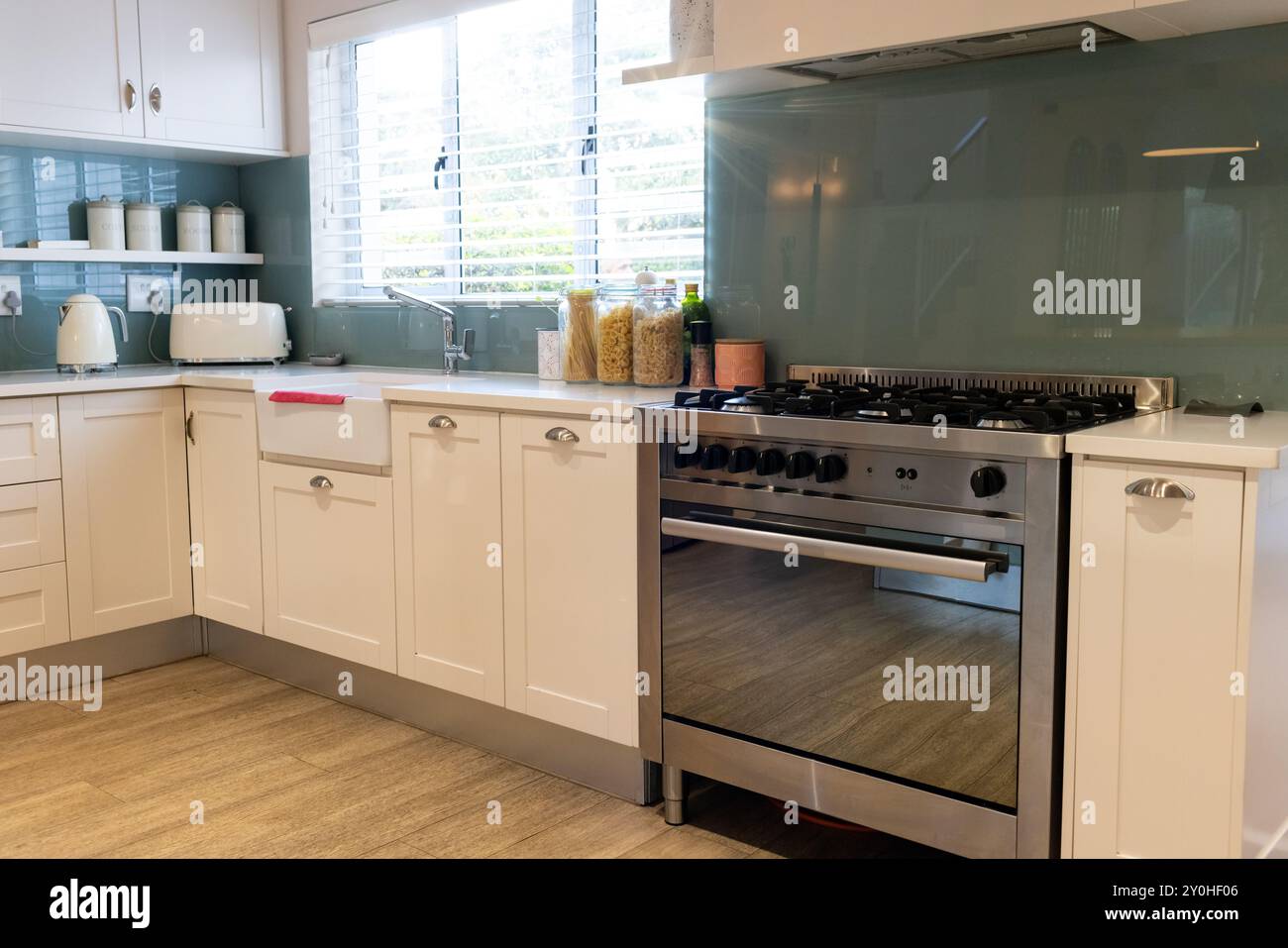 Modern kitchen with stainless steel stove, white cabinets, and ...