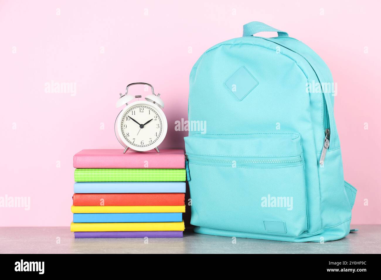 Backpack with different school stationery and alarm clock on light grey ...