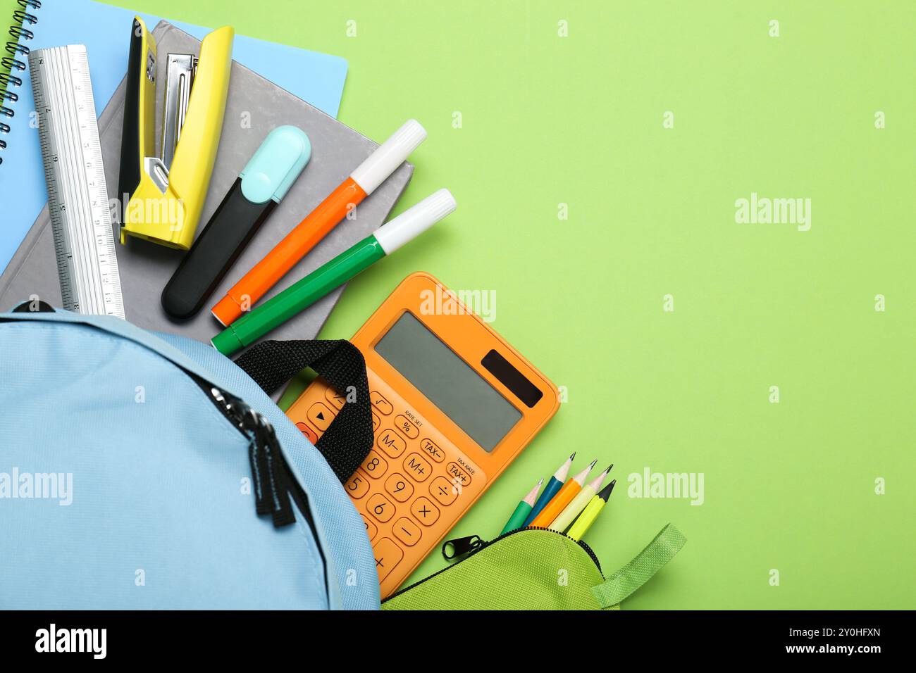 Light blue school backpack with stationery on green background, top ...