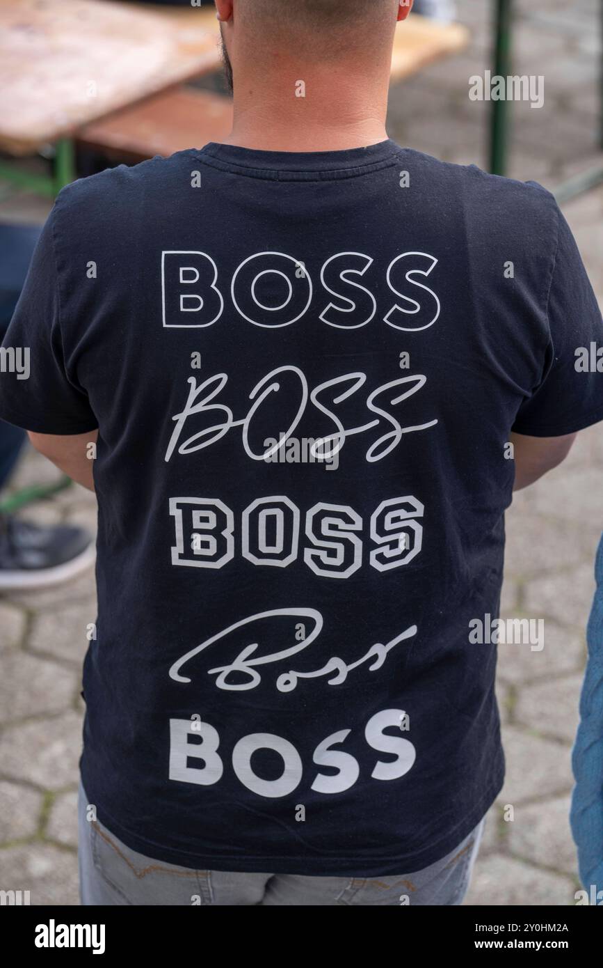 Mann mit T-shirt, darauf der Name Boss, Markenname in verschiedenen ...