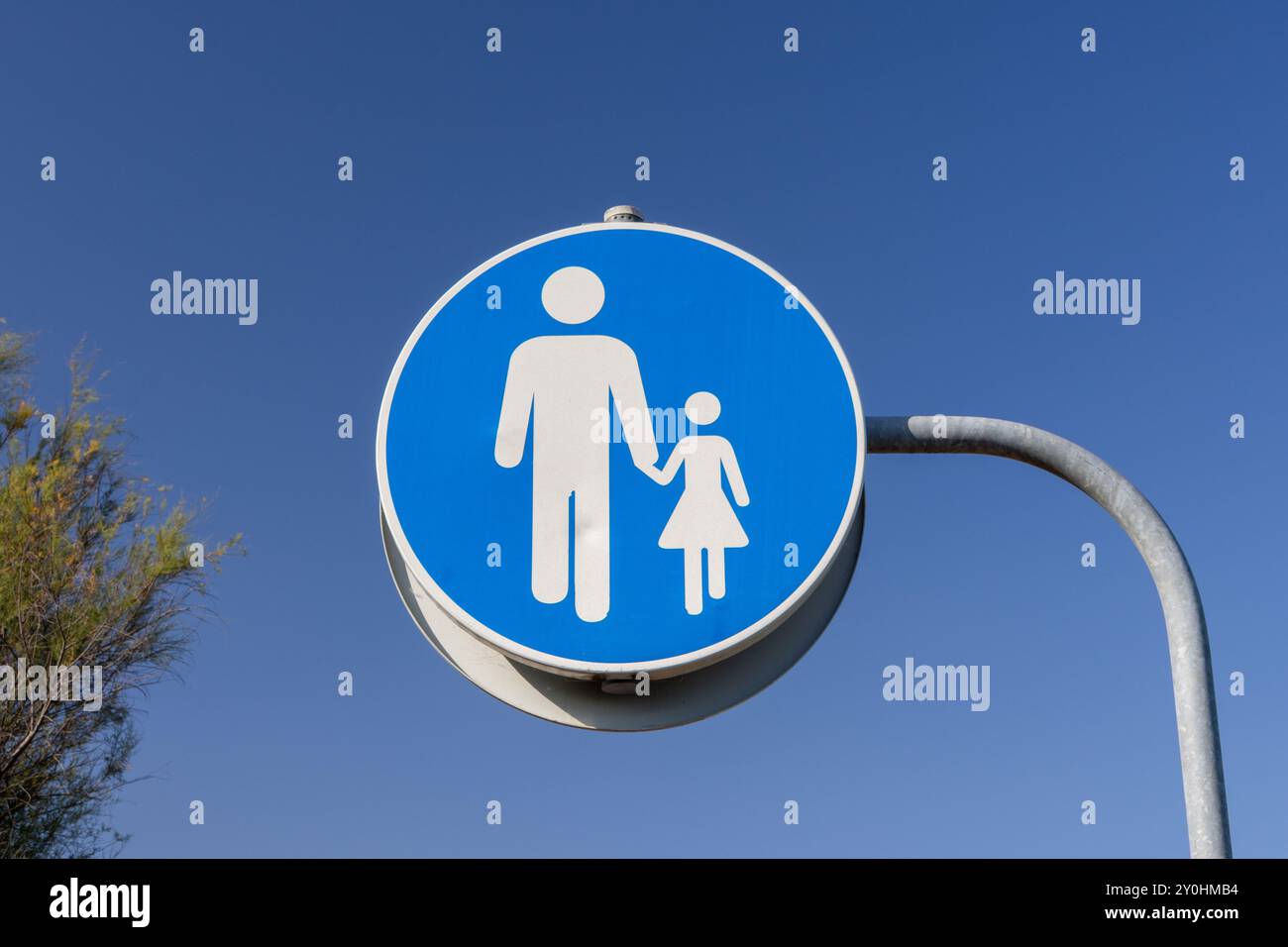 Round blue pedestrian sign showing an adult and a child holding hands ...