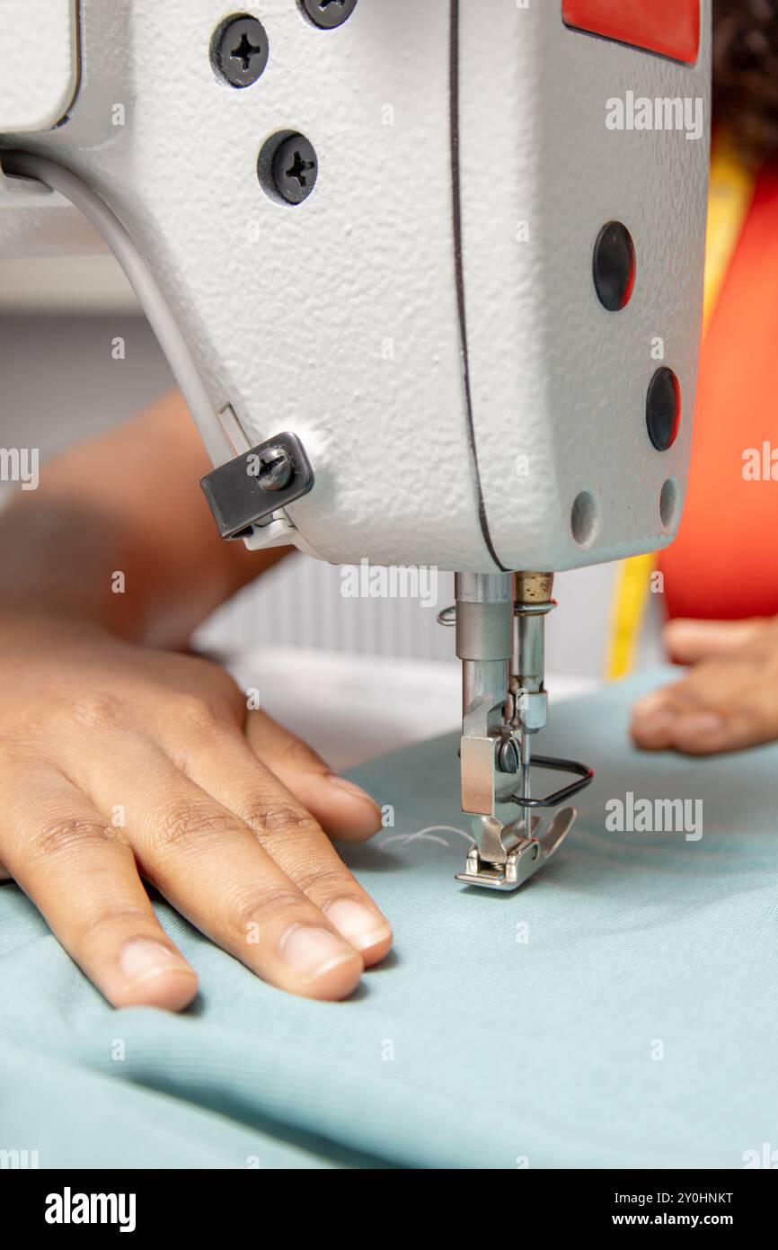 Woman hands sewing fabric on sewing machine highlighting the needle and ...