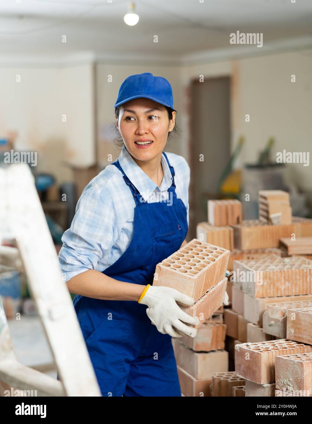 Female builder carrying bricks at renovating object Stock Photo - Alamy