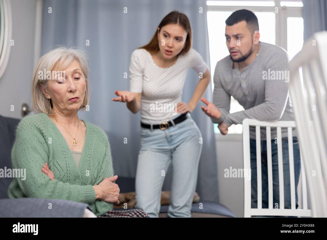 Senior woman ignoring adult couple scolding her Stock Photo - Alamy