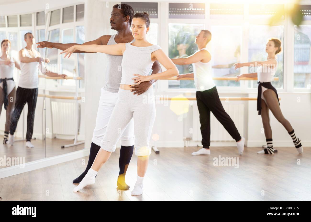 Female ballet amateur dancer practicing with partner at group class ...