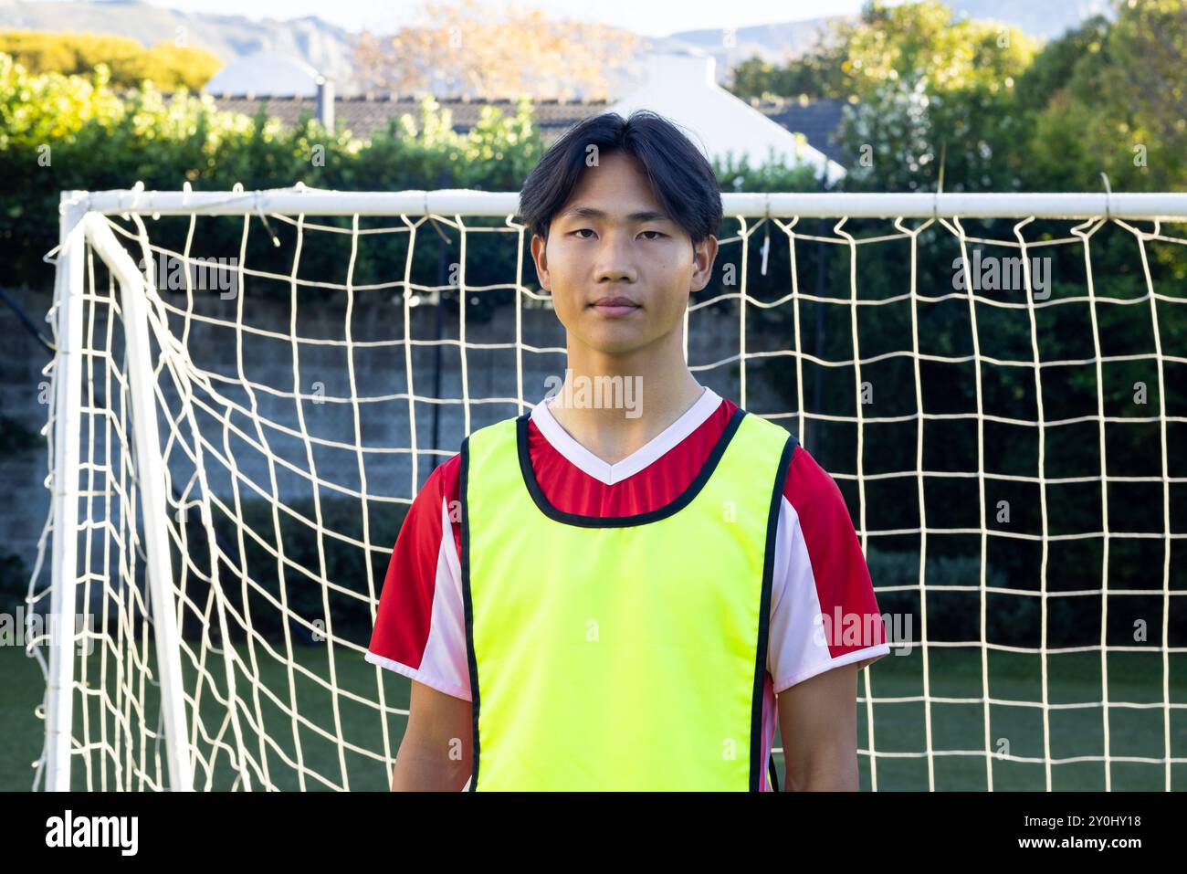 Standing in front of goalpost, teenage male soccer player wearing ...