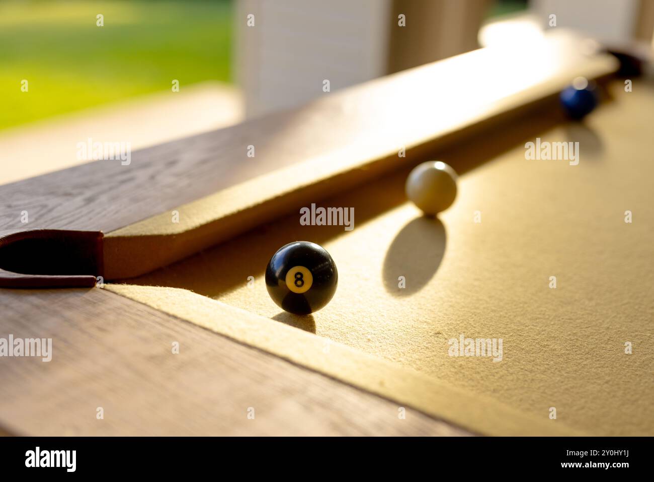 Playing billiards, black eight ball near pocket on pool table, sunny ...