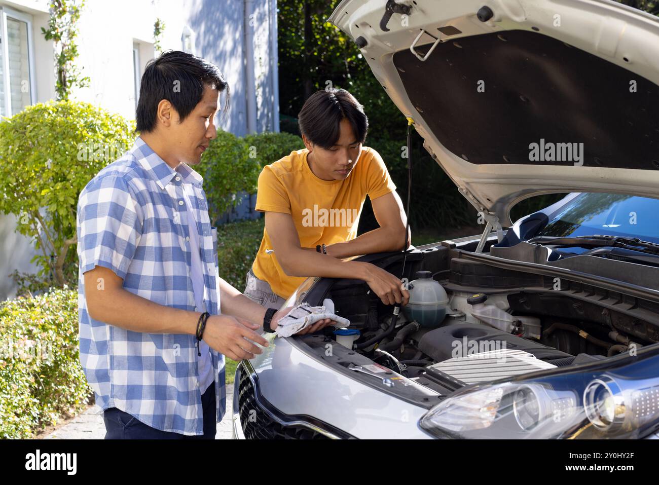 Checking car engine, father and son performing maintenance together ...