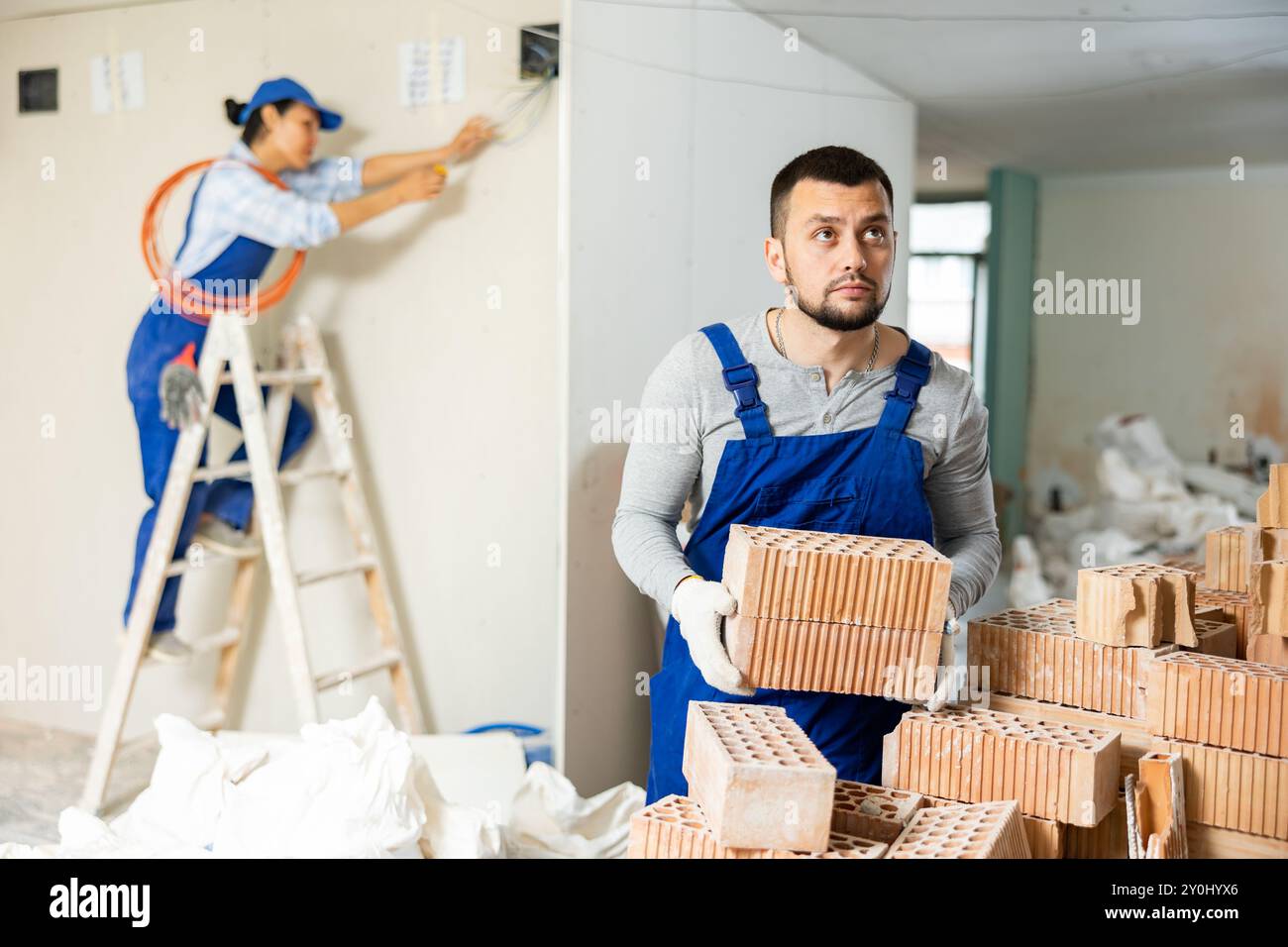 Man builder carrying bricks hi-res stock photography and images - Alamy