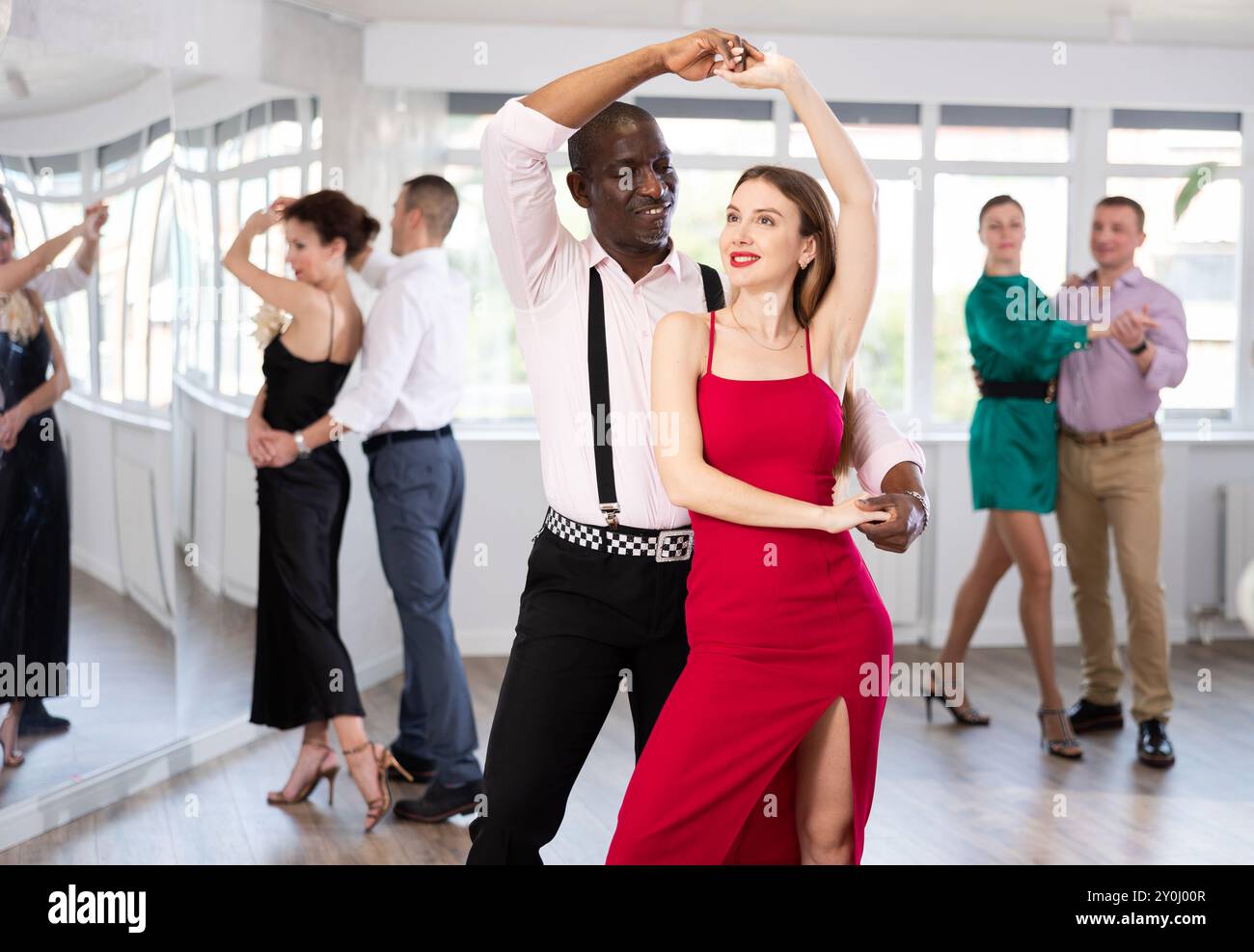 Woman with African man dancing waltz in couple during lesson at studio ...