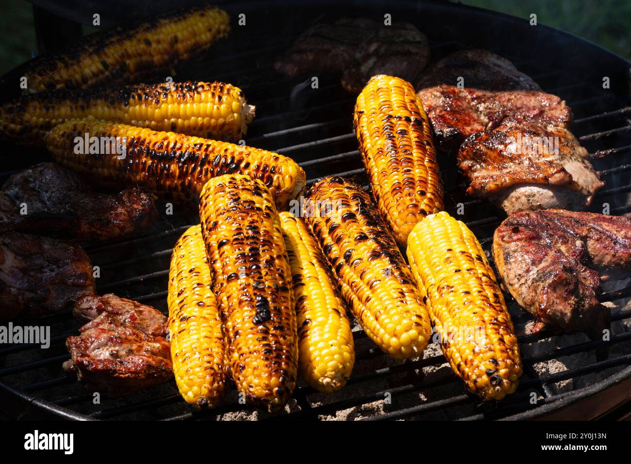 A barbecue grill with corn and meat, showcasing the beautifully charred ...
