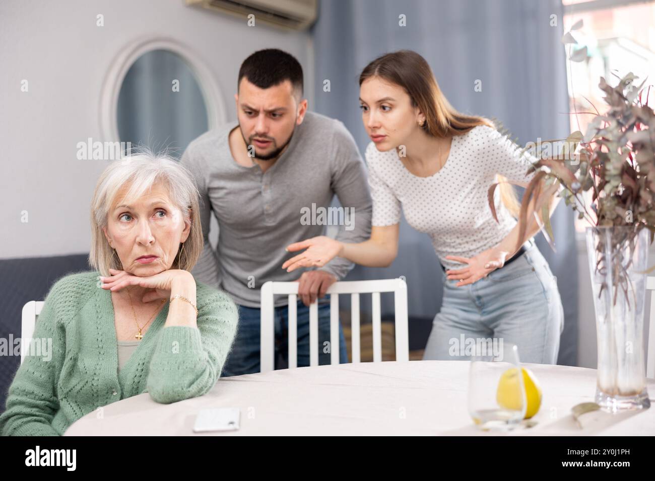 Senior woman ignoring adult couple scolding her Stock Photo - Alamy
