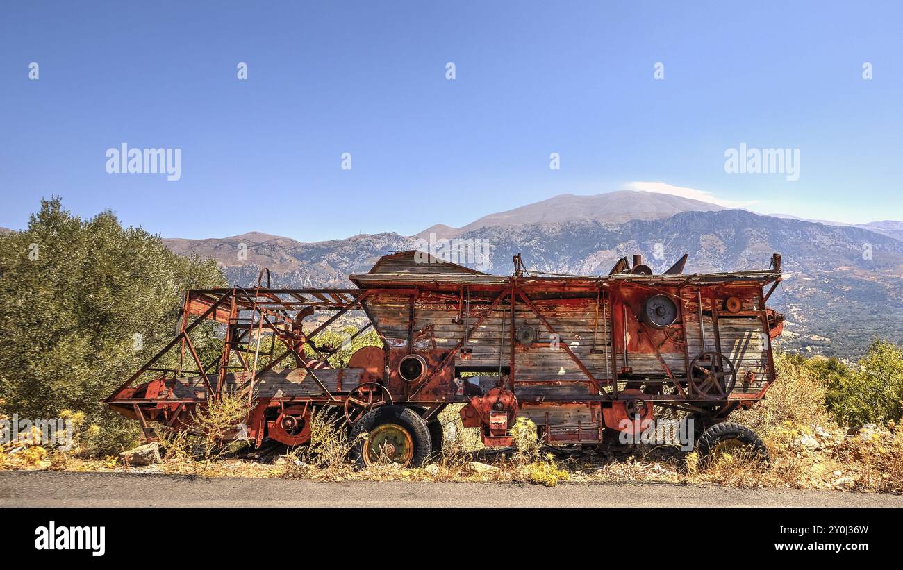 Antique, rusty combine harvester in front of a mountain backdrop under ...
