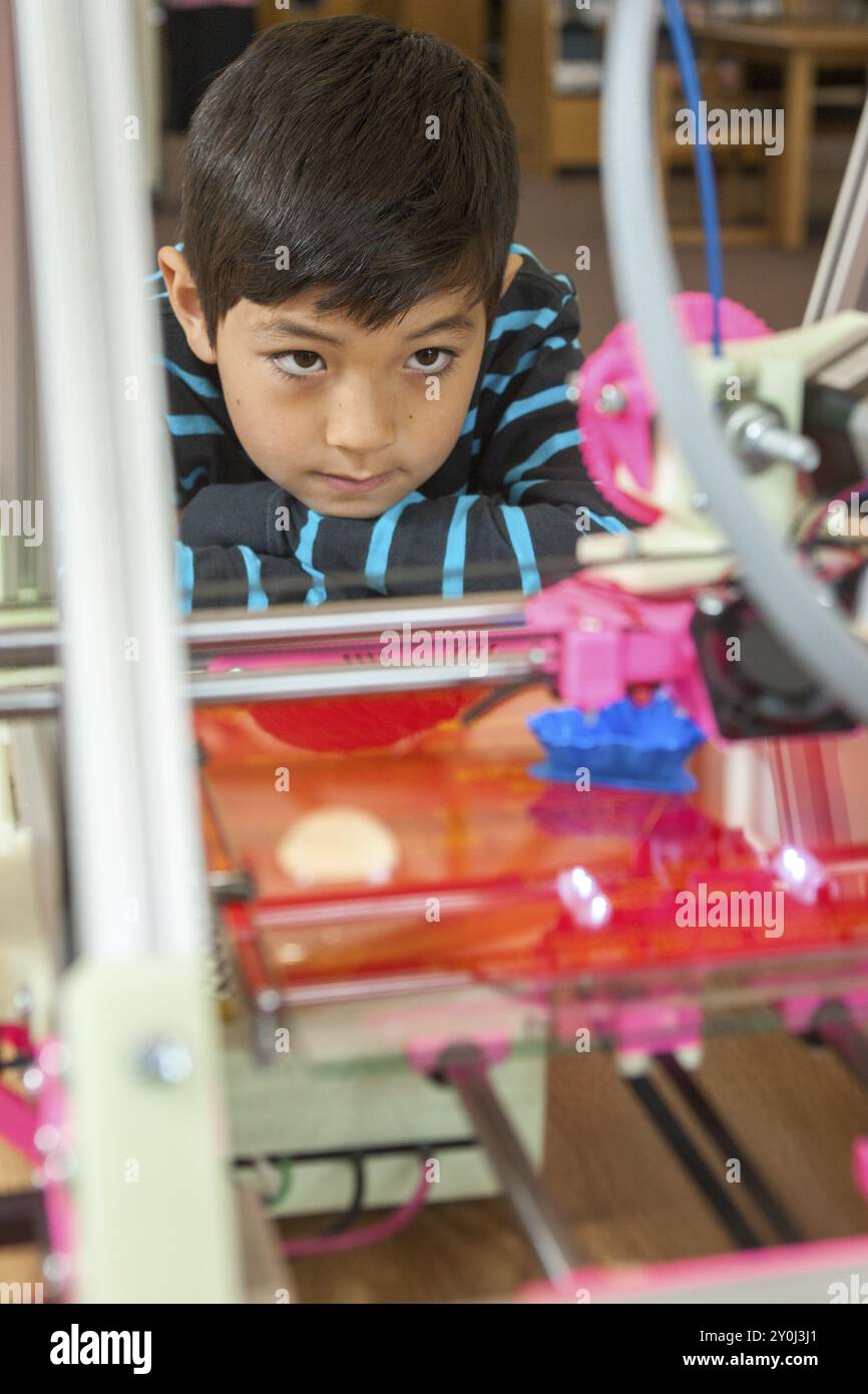 A young boy watches as a 3D printer prints an object Stock Photo - Alamy