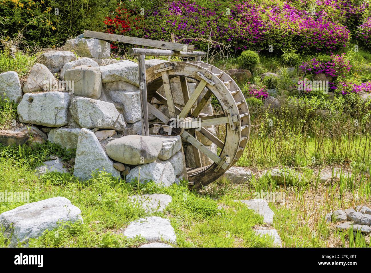 Old wooden water wheel in dried stream bed with background of colorful ...