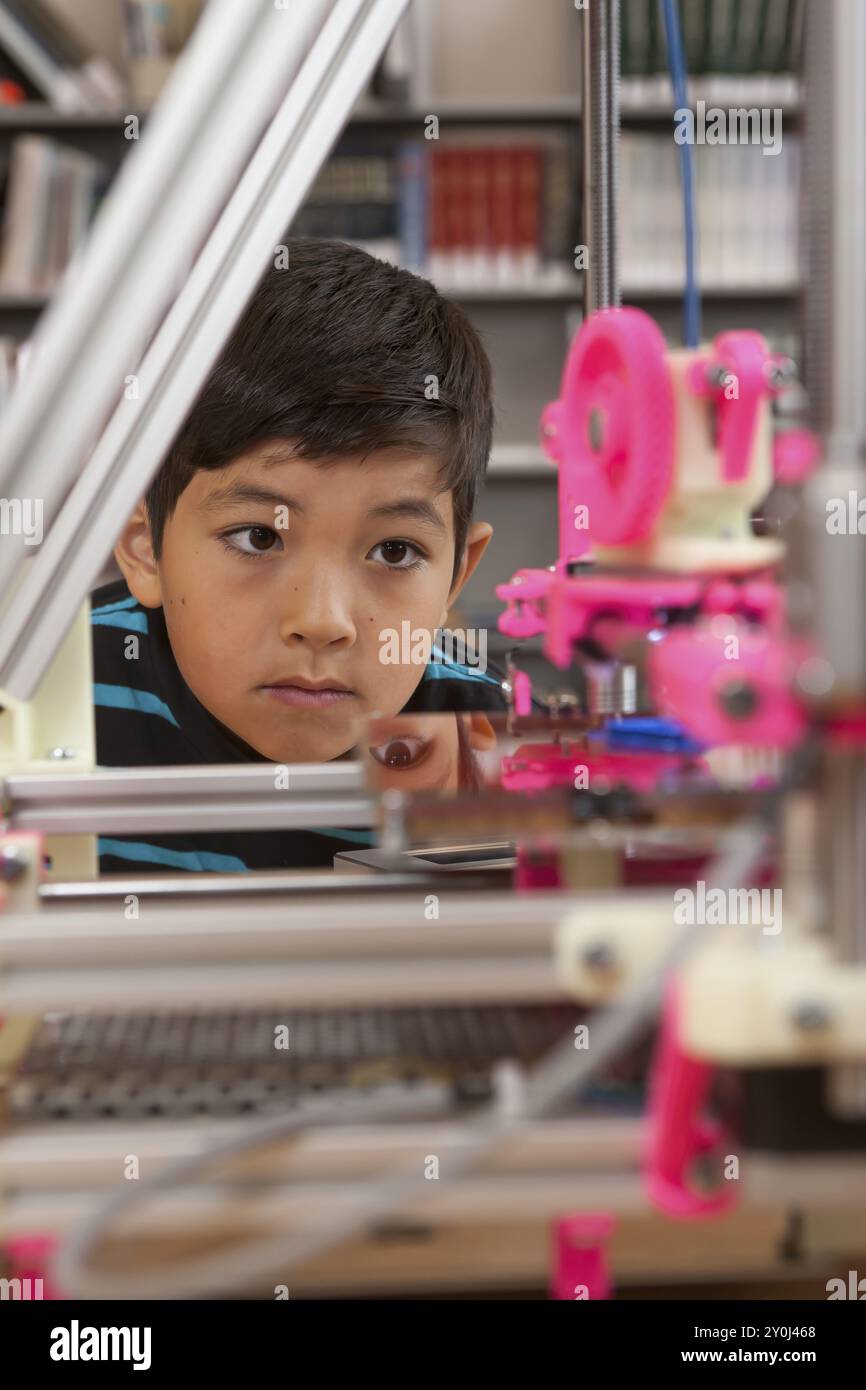 A young boy watches as a 3D printer prints an object Stock Photo - Alamy