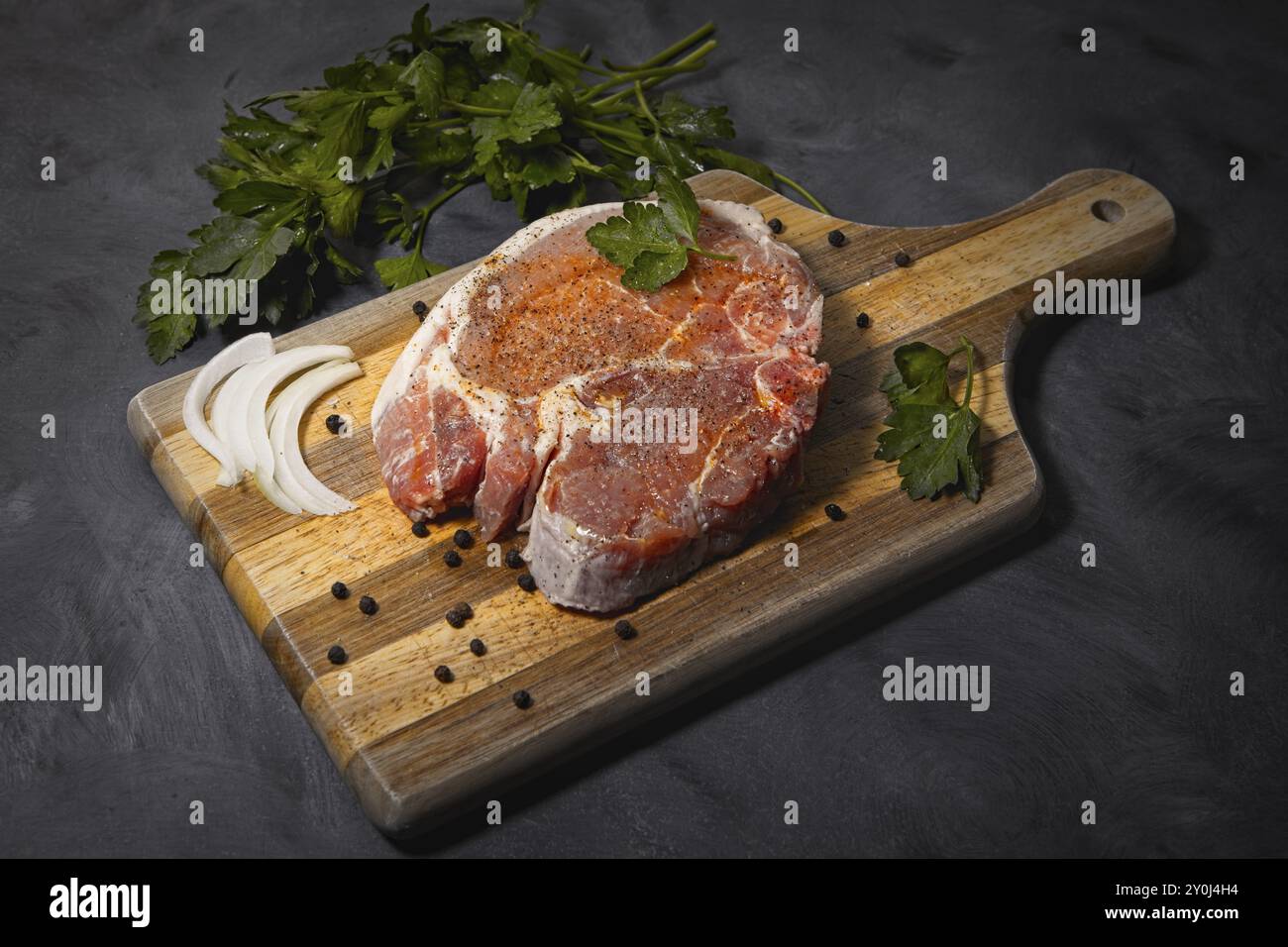 An overview of a raw pork chop cutlet on a wooden cutting board with ...