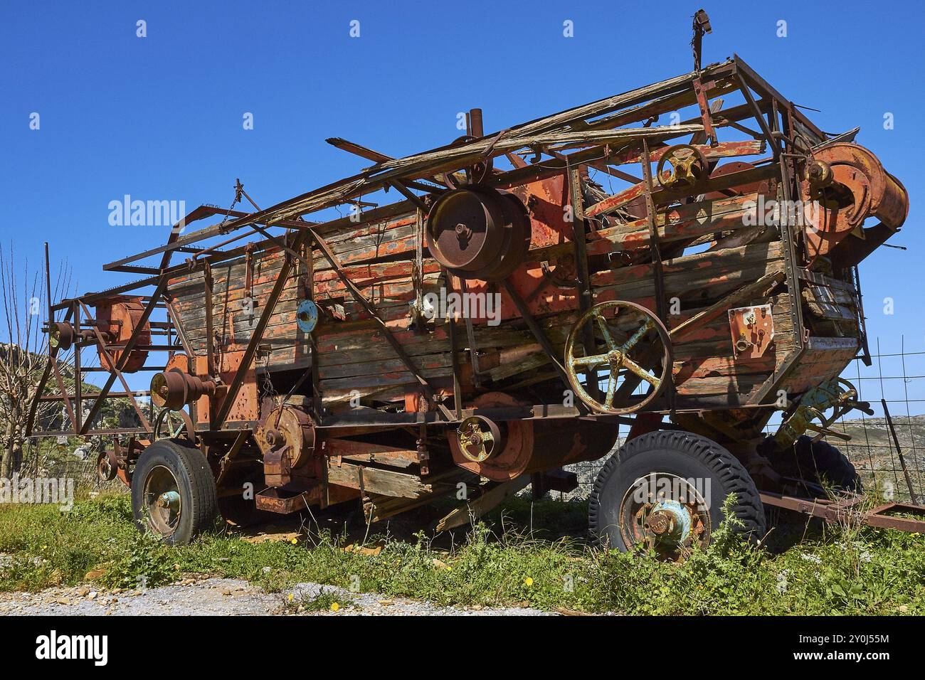 Rusty old combine harvester on green fields under blue sky, wrecked ...