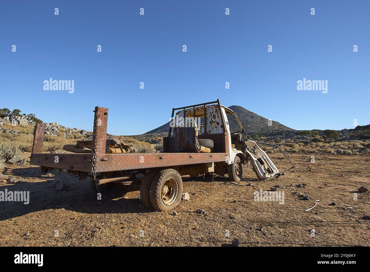 A badly decayed lorry, its loading area exposed, stands in a dry desert ...