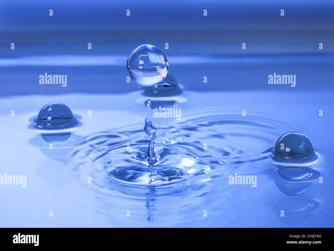A water bead creates a small splash in shallow water Stock Photo - Alamy