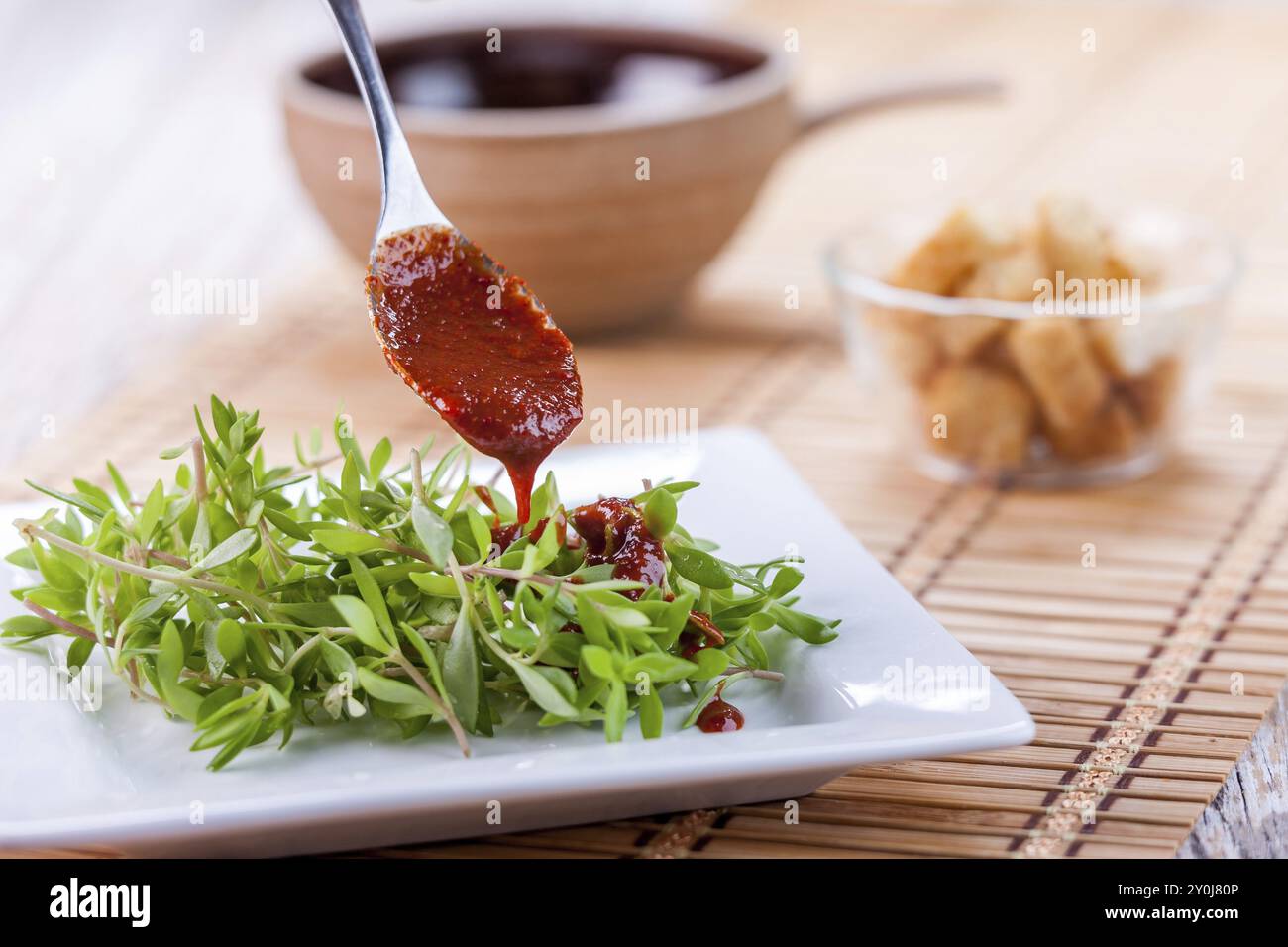 Pouring red pepper paste onto a plate of edible creeping sedum Stock ...
