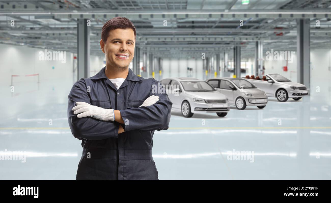 Auto mechanic worker in a uniform posing with crossed arms at a car ...