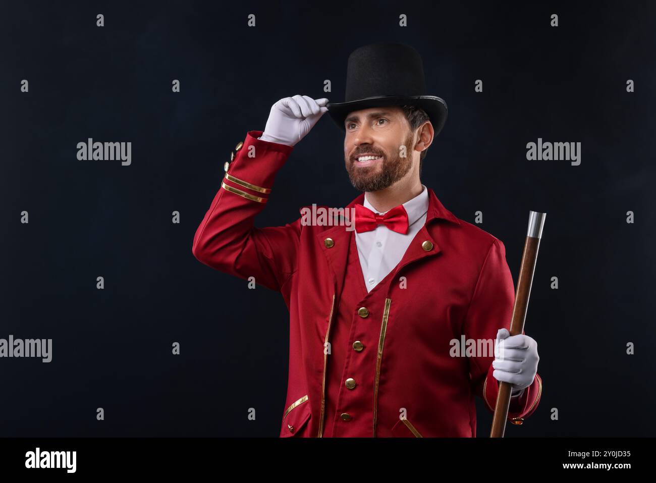 Portrait of showman in red costume and hat on black background with ...