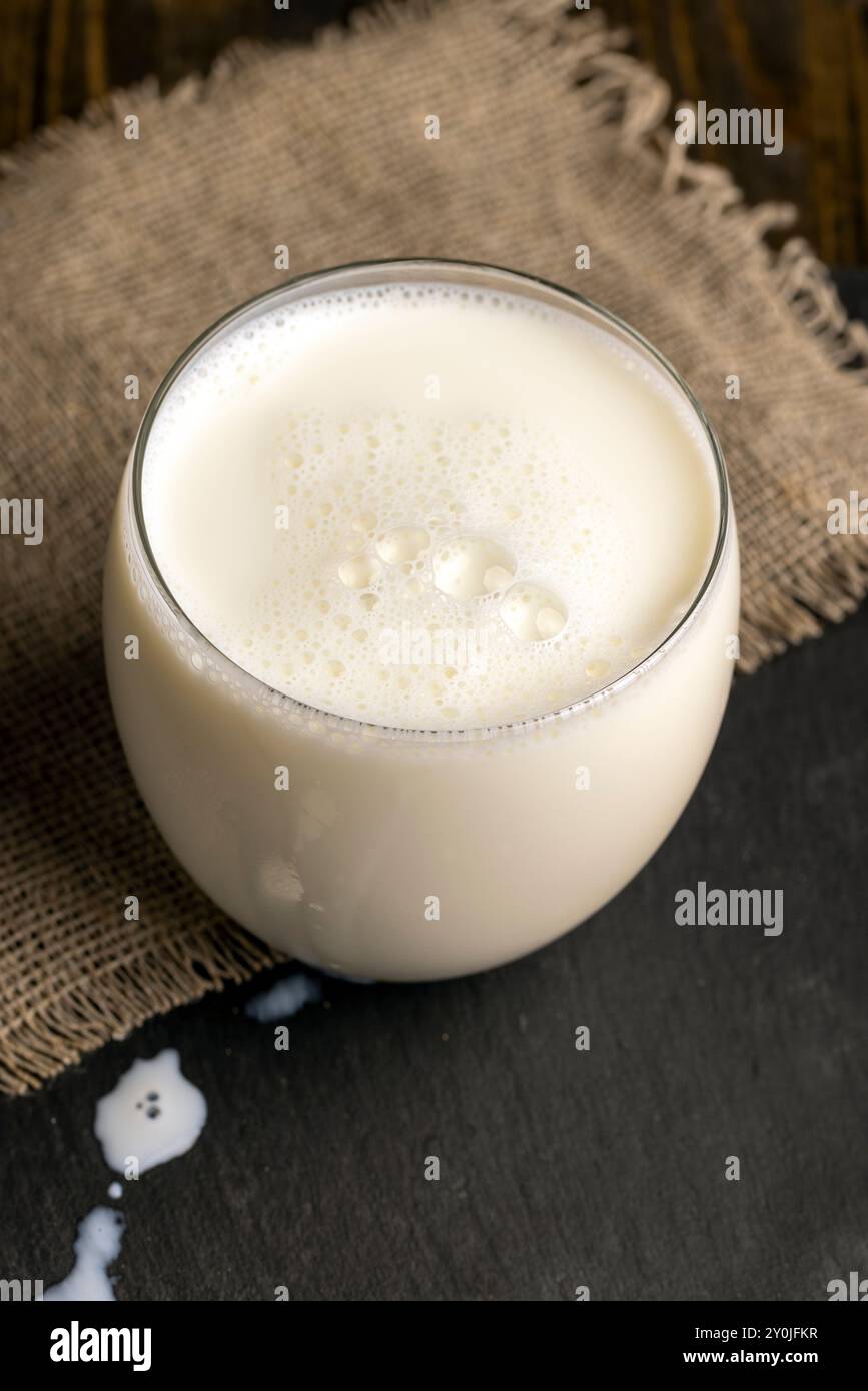 White cow's milk poured into a transparent glass on the table, fresh ...
