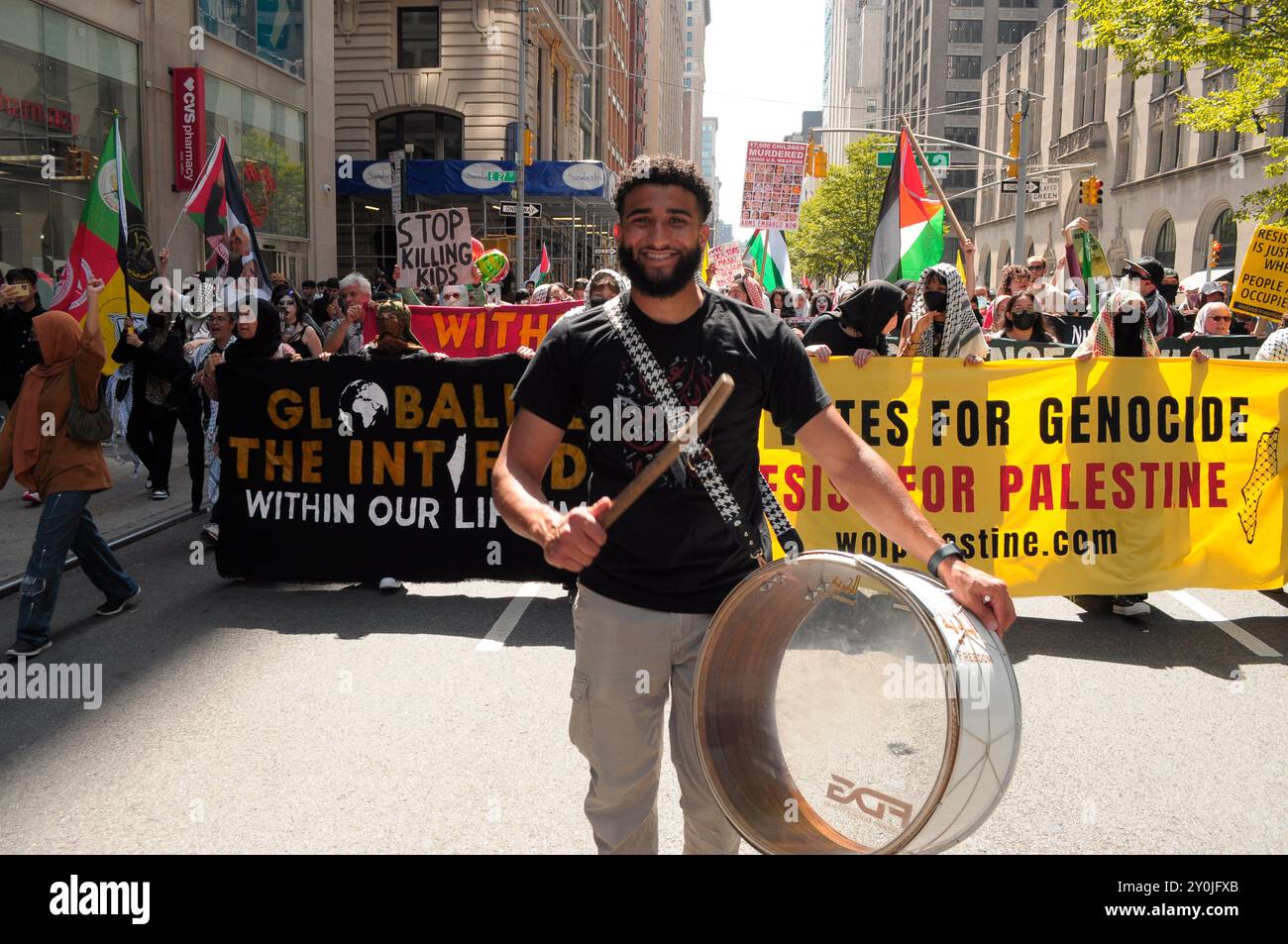 A pro-Palestine demonstrator marches while playing a drum. Pro ...