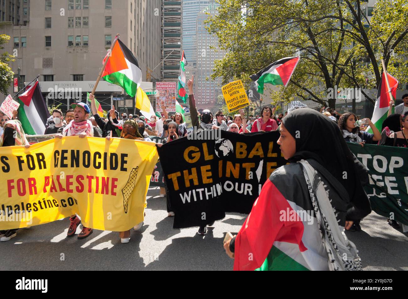 Pro-Palestine demonstrators march holding banners and waving ...