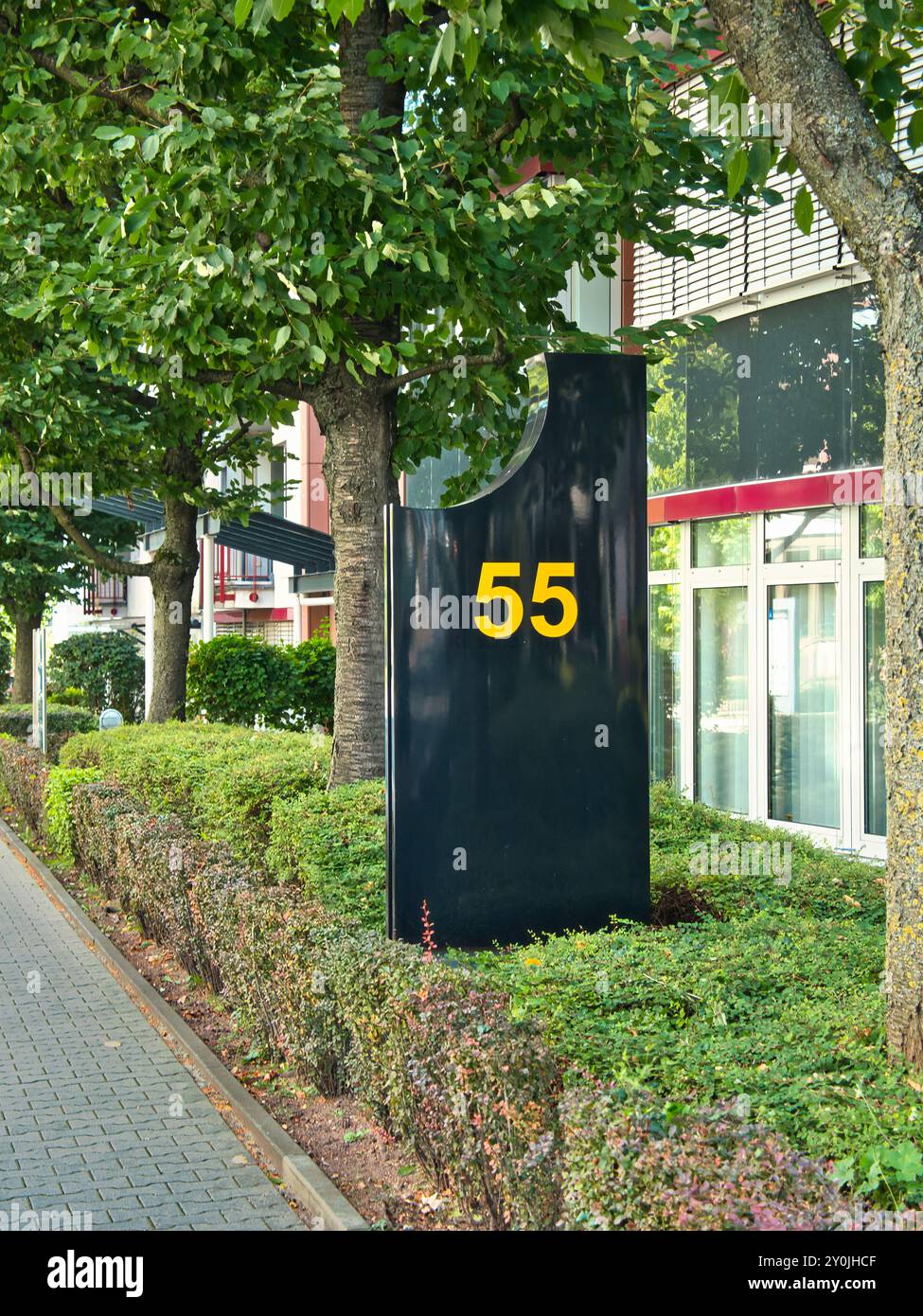A house number plate stands in a green area with the number 55 on it ...