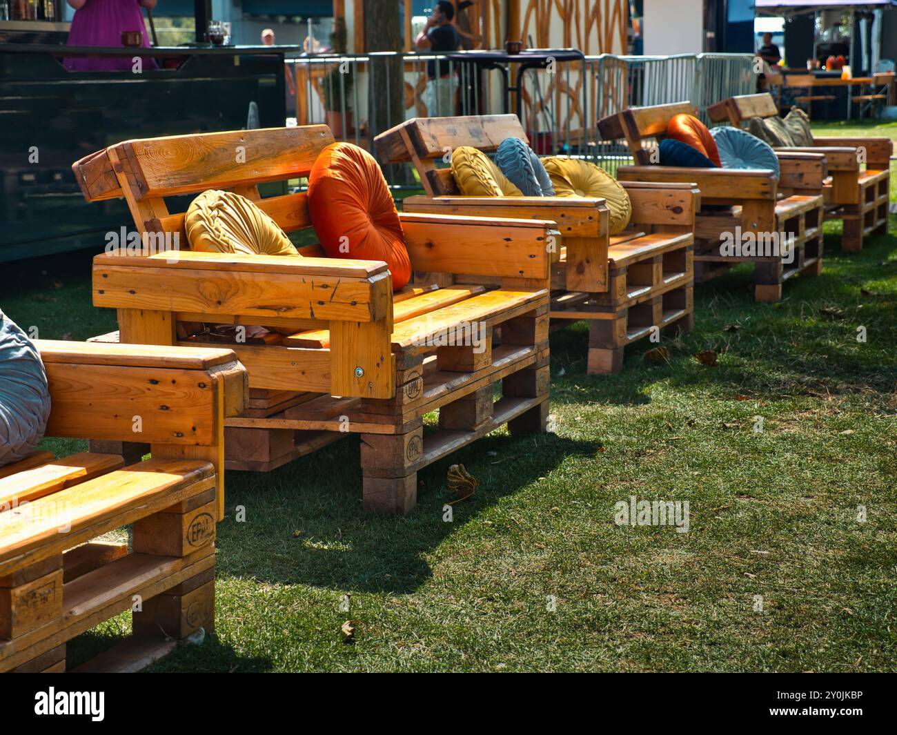 Seating made from pallets, with colorful cushions on a green area and ...