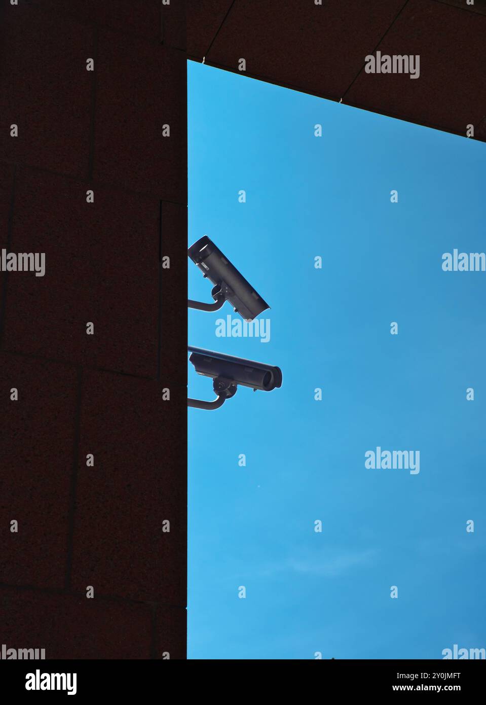 The detailed shot of two surveillance cameras in strong contrast to the ...