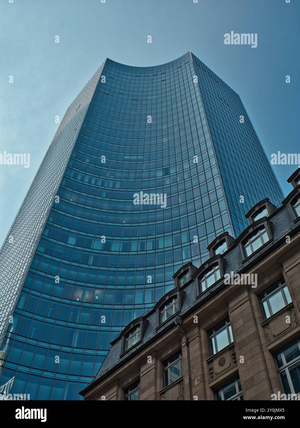 A skyscraper photographed from below with its own historic building in ...