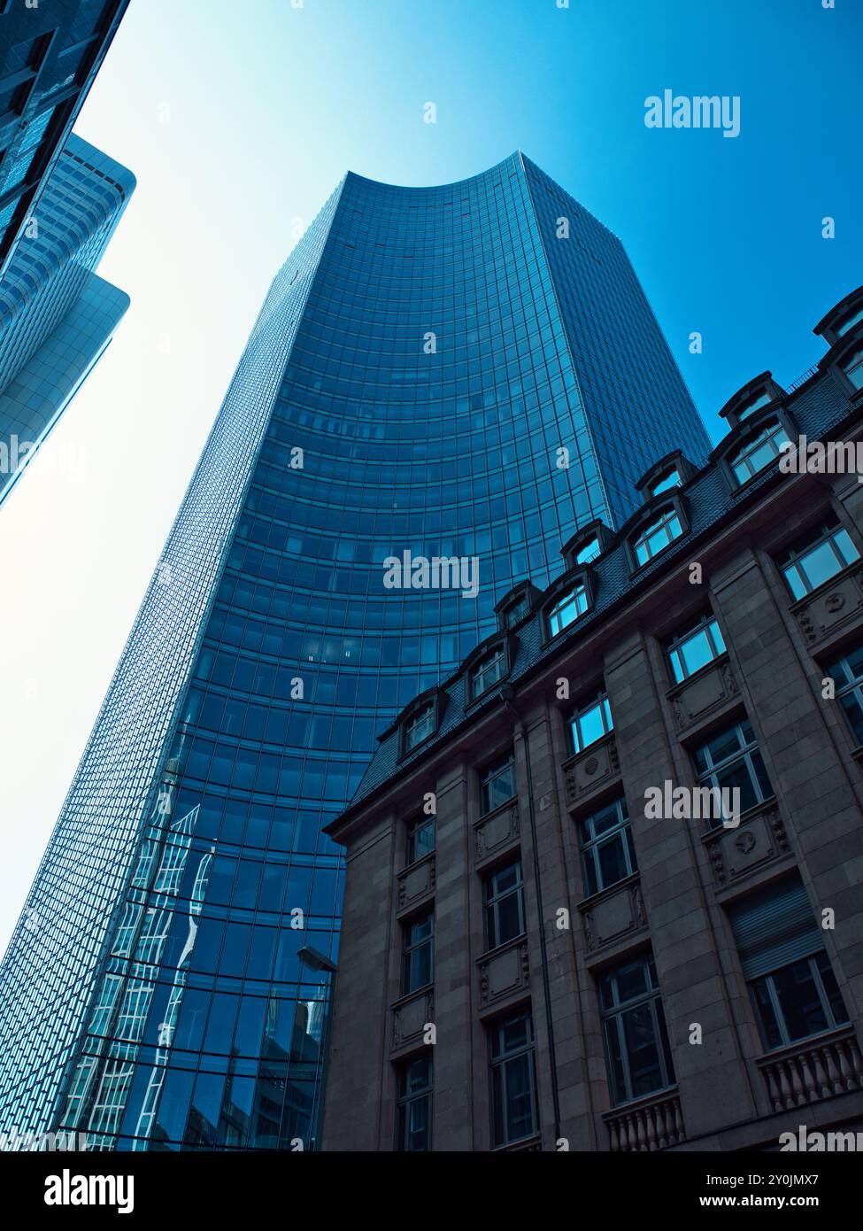 A skyscraper photographed from below with its own historic building in ...