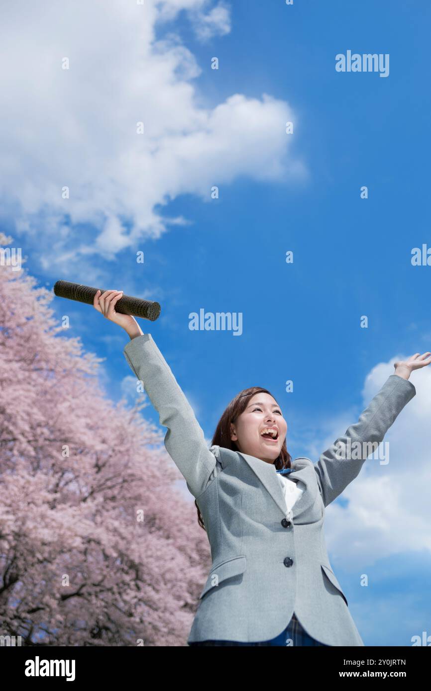 Schoolgirl doing Banzai cheer while holding their diplomas with Cherry ...