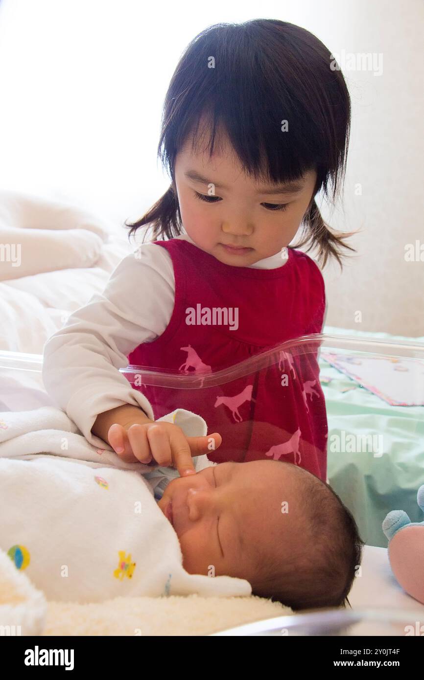 Girl touching a baby Stock Photo - Alamy