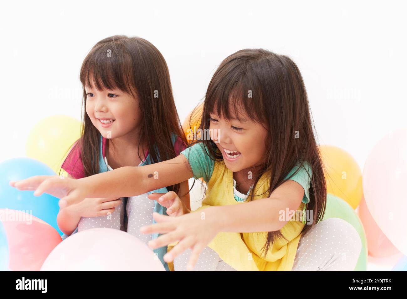 Twin sisters playing with balloons Stock Photo - Alamy