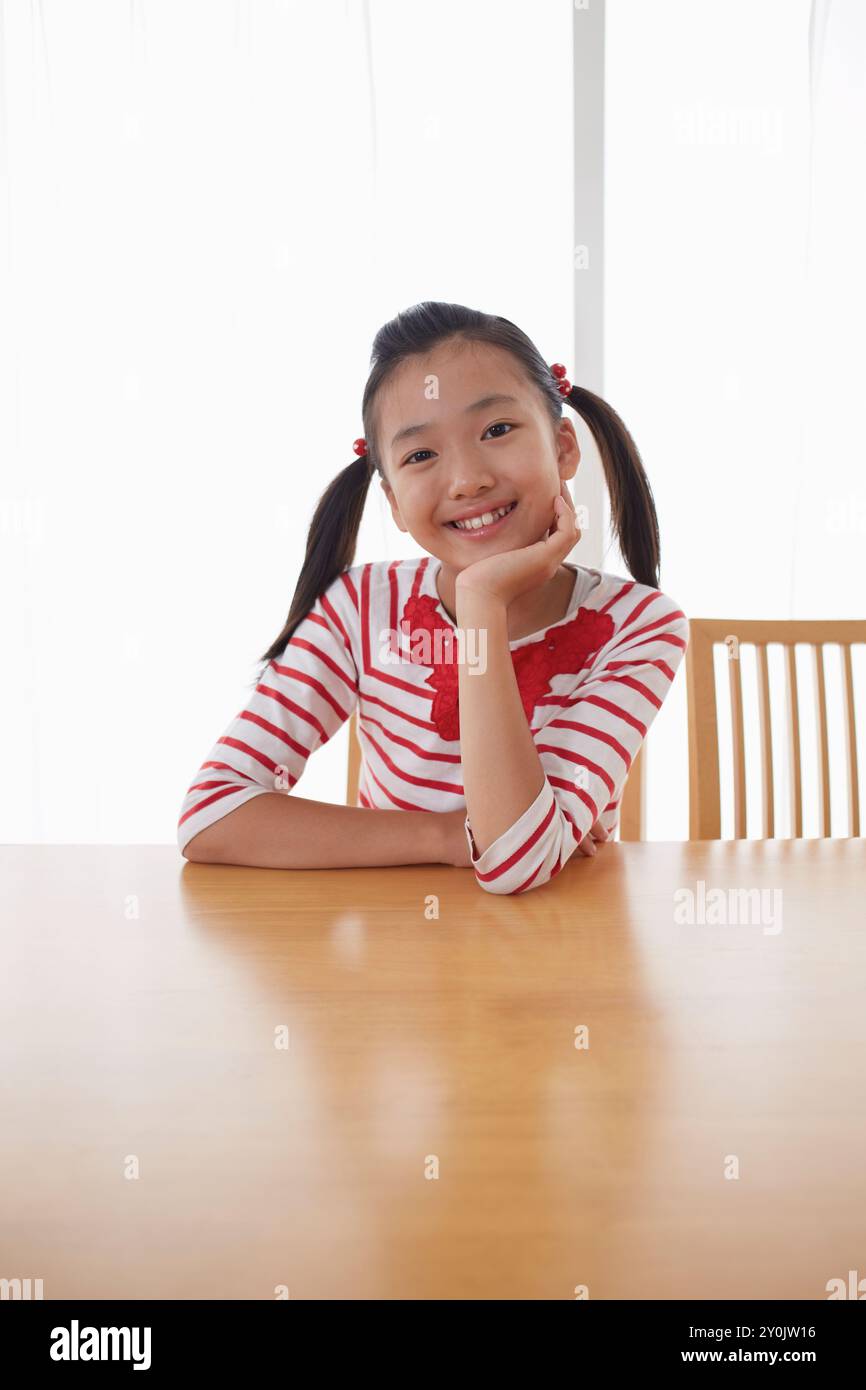Girl resting her chin in her hands at the dining table Stock Photo - Alamy